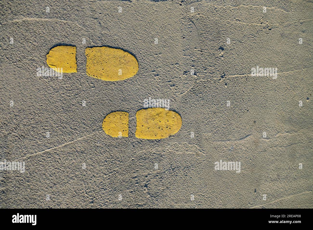 Two yellow shoeprints on concrete pavement Stock Photo - Alamy