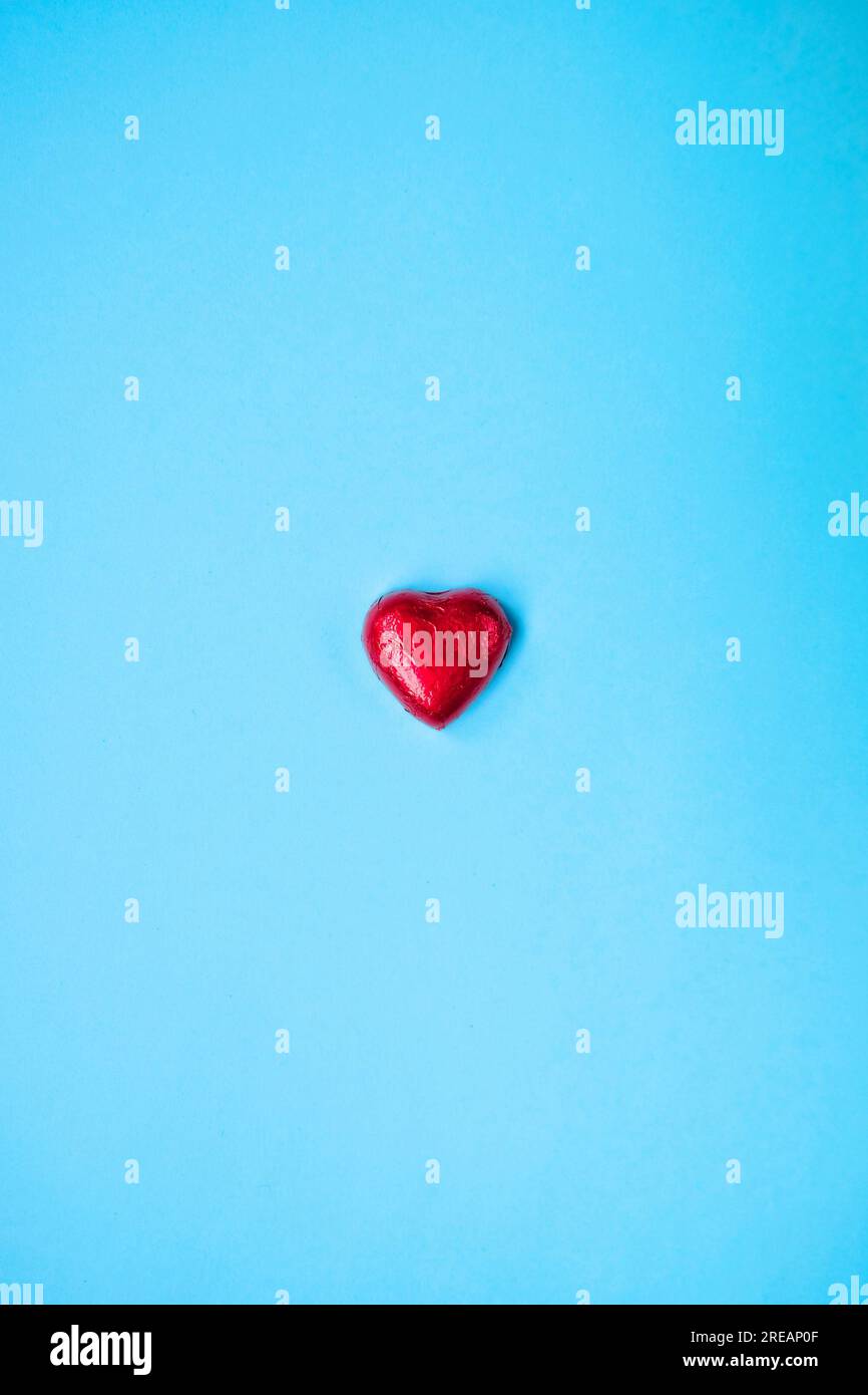 A single small red heart on a blue background, a chocolate candy ...