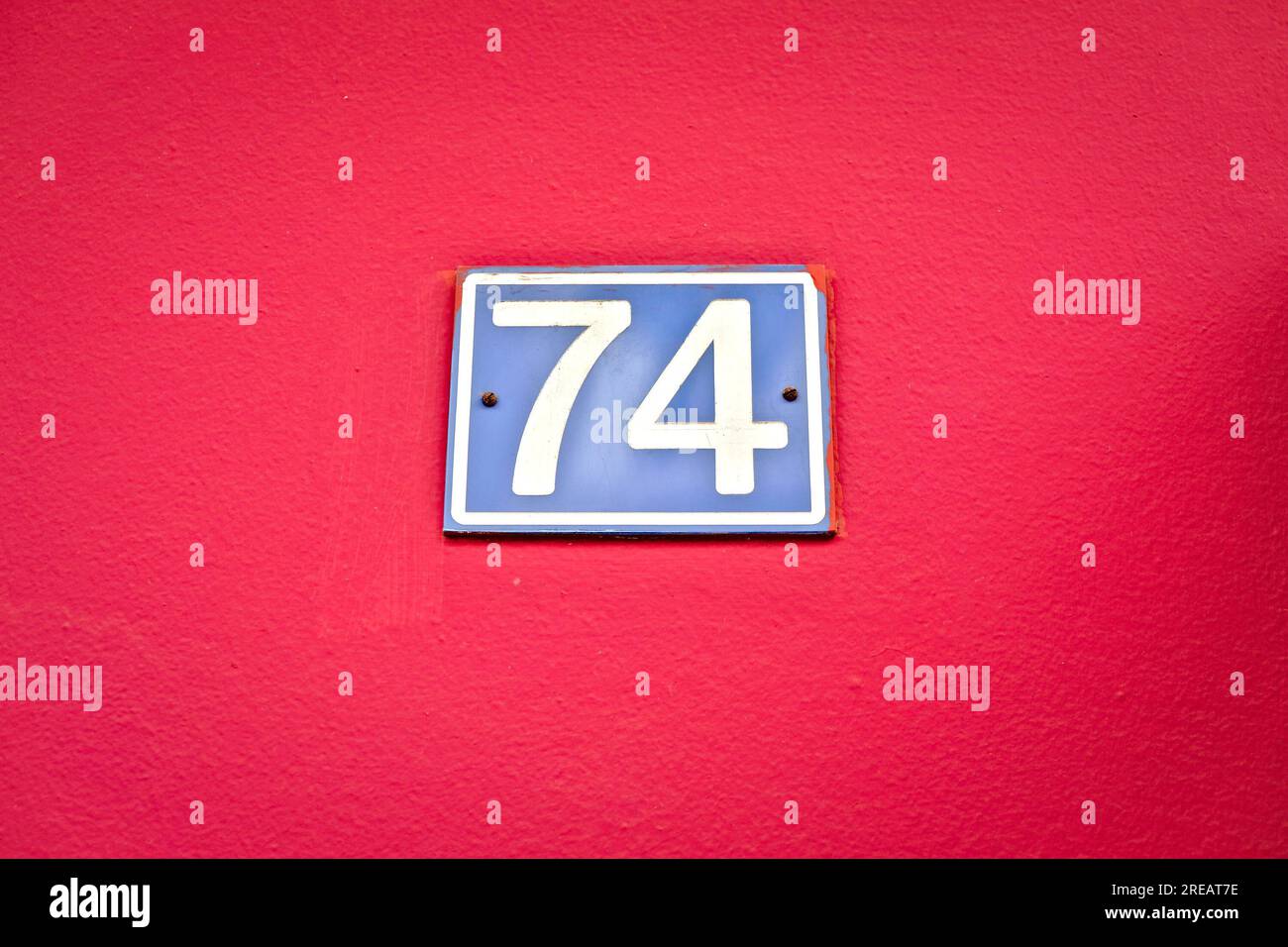 Number 74, seventy-four, blue plate on an intensive red background ...