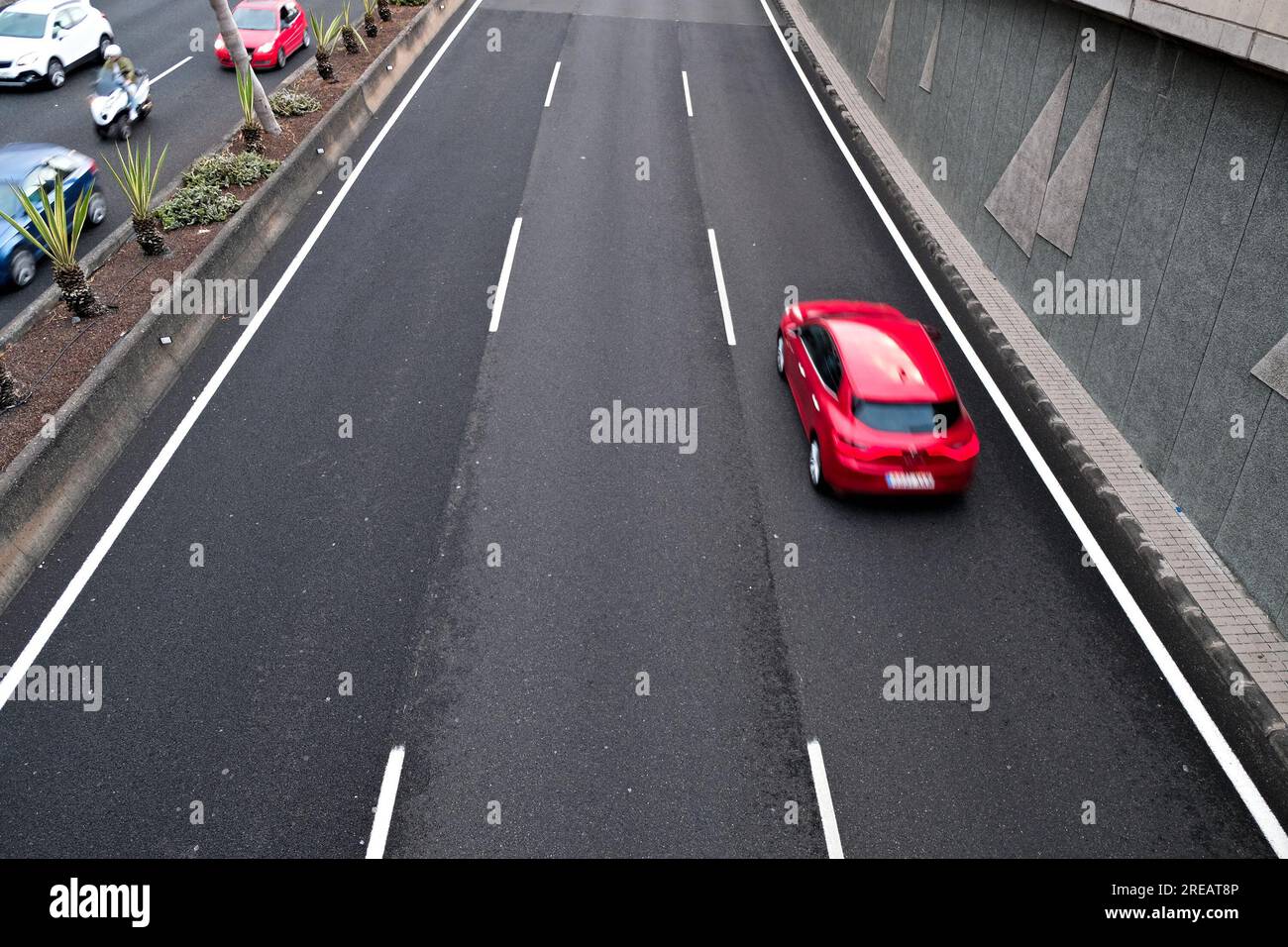 A sporty red car in movement on a black asplalt road, light trails and ...