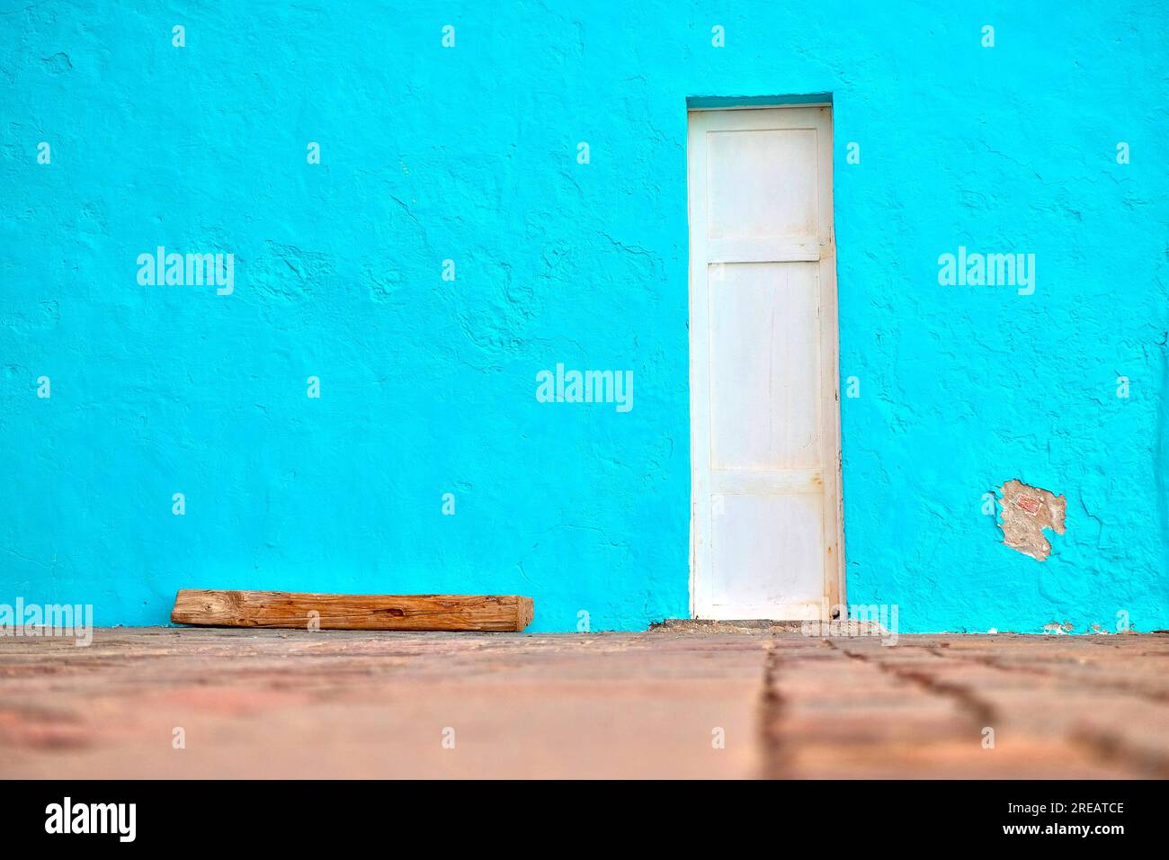 Narrow white door in a simple blue wall. Minimal Mediterranean village ...