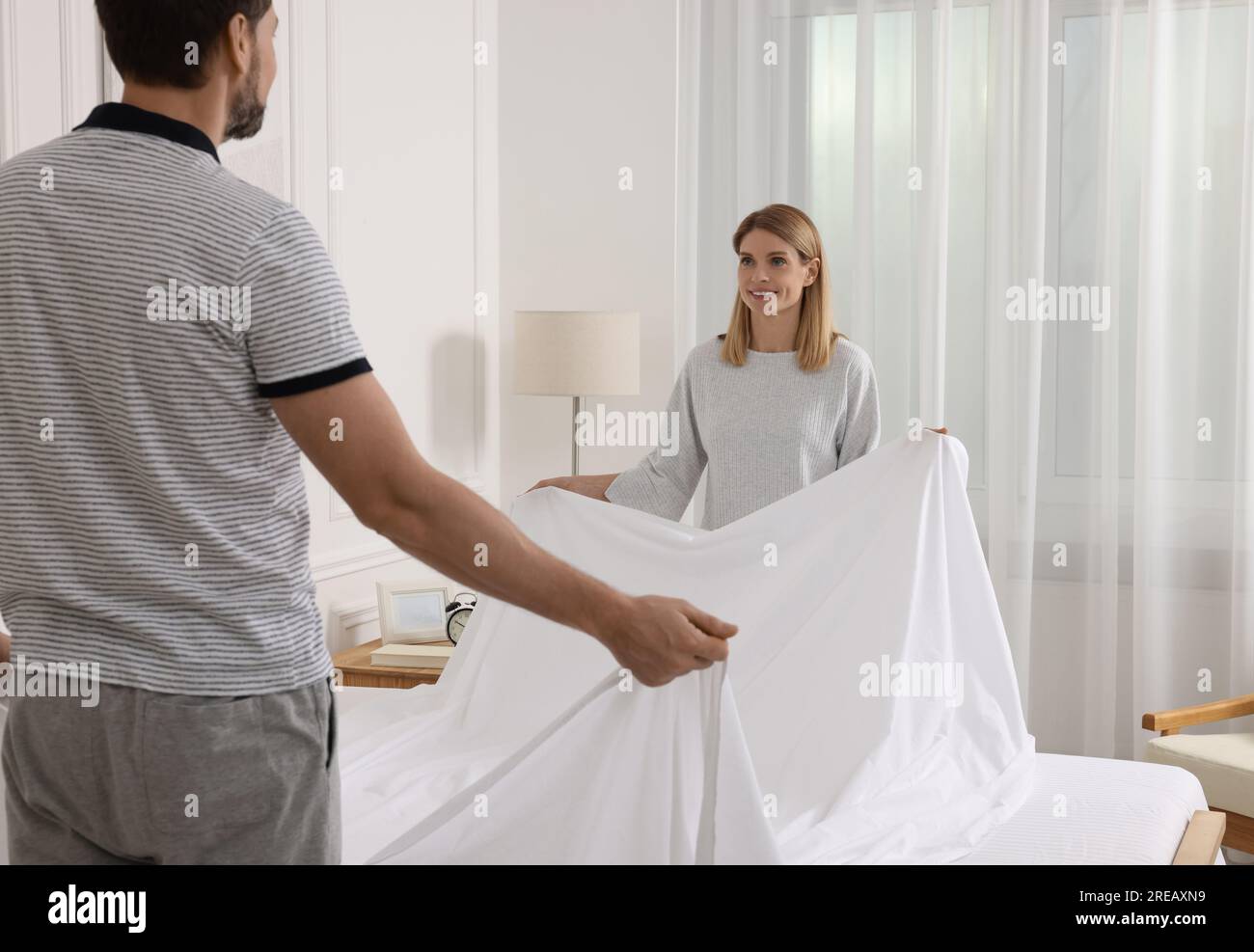 Couple changing bed linens in room. Domestic chores Stock Photo - Alamy