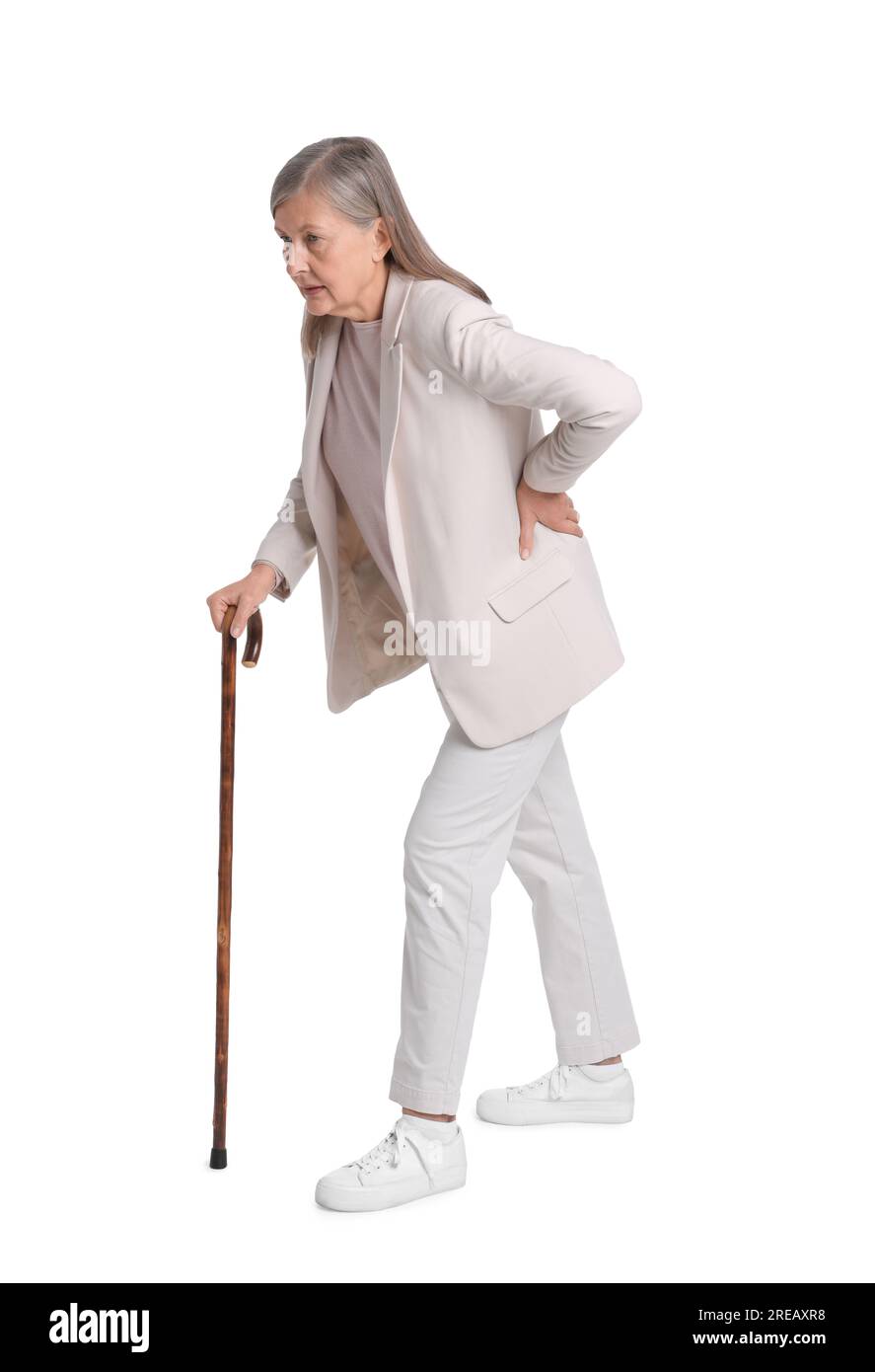 Senior woman with walking cane suffering from back pain on white ...