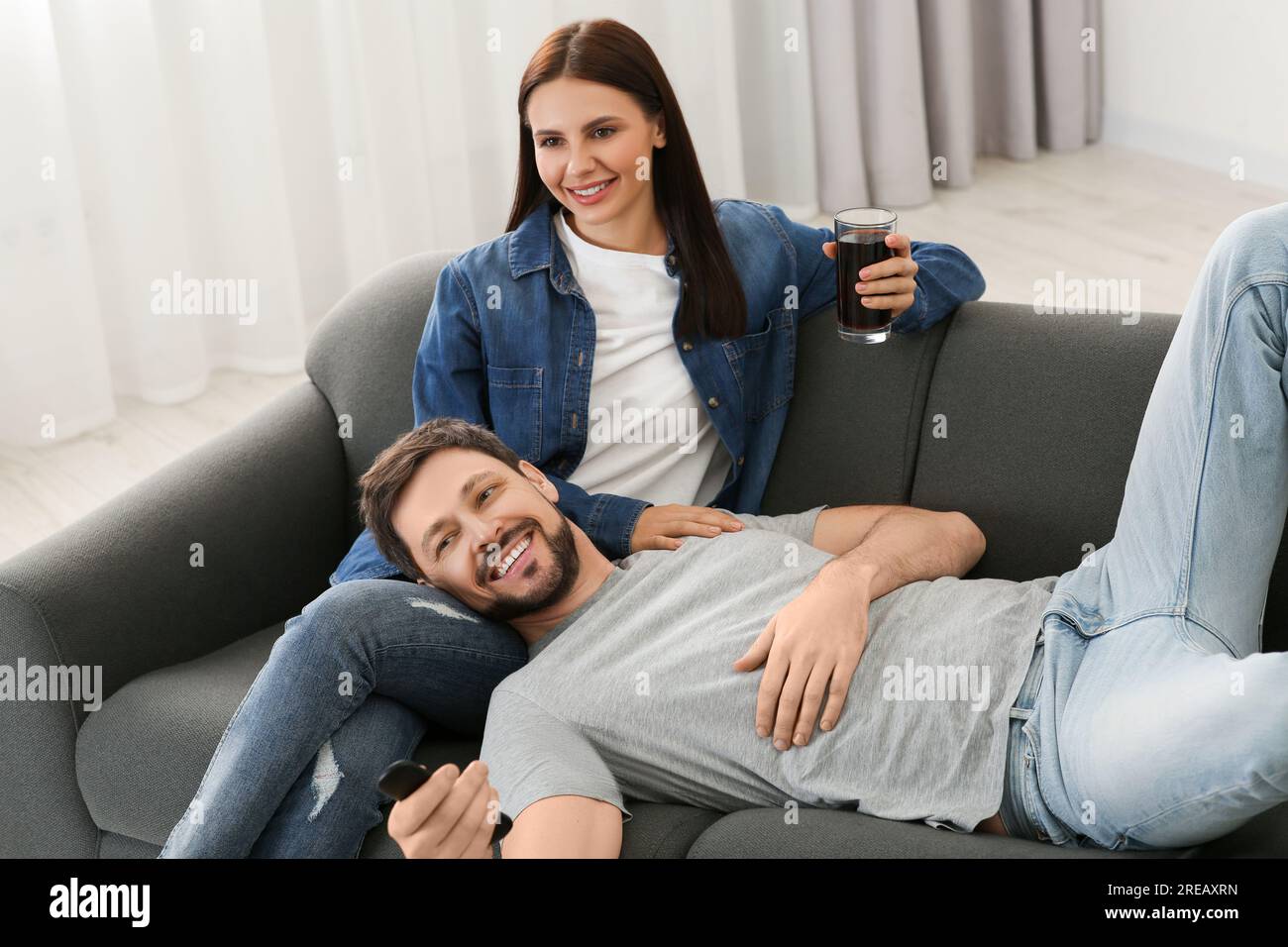 Happy couple watching show at home. Man changing TV channels with ...