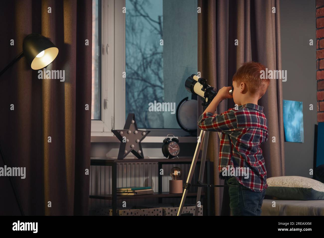 Little boy looking at stars through telescope in room, back view Stock ...