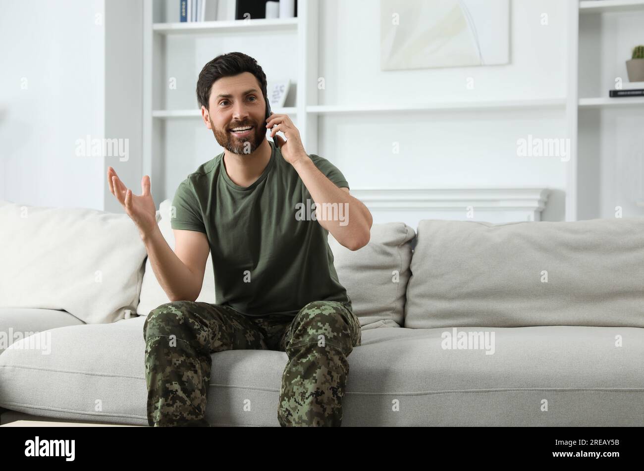 Happy soldier talking on phone in living room. Military service Stock ...