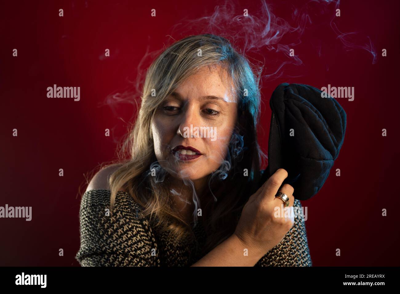 Attractive and confident woman holding a black beret next to her face ...