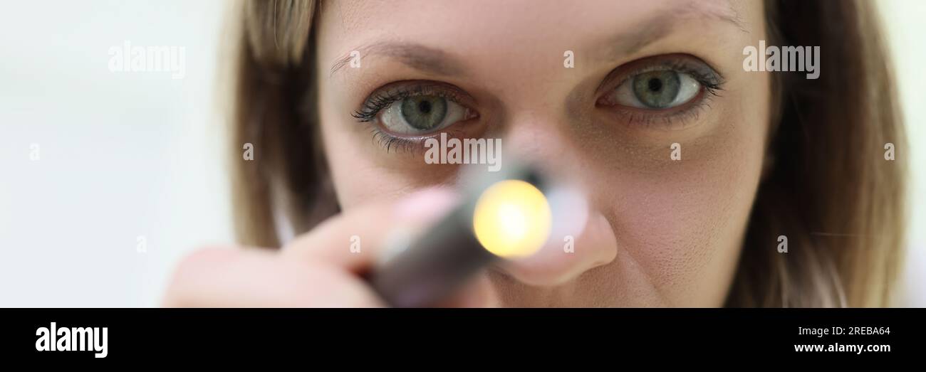 Doctor anesthesiologist resuscitator shining medical flashlight into ...