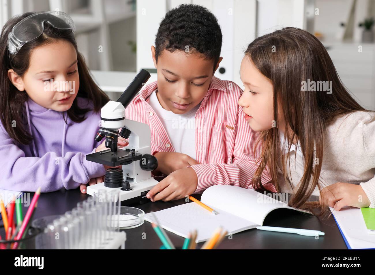 Little children with microscope studying Chemistry in science classroom ...