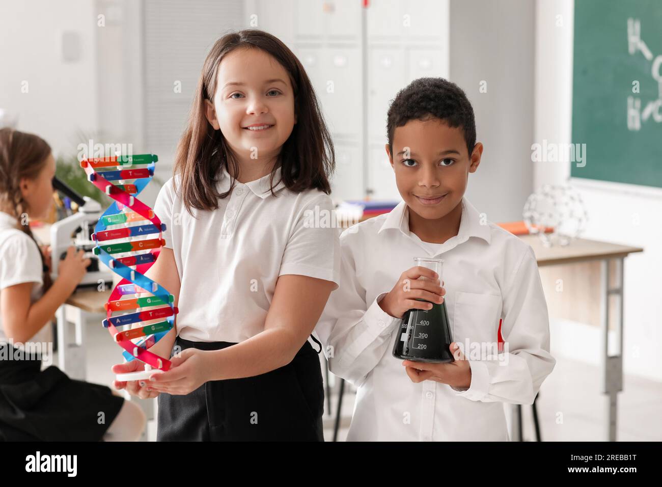 Little children with molecular model and flask in science classroom ...