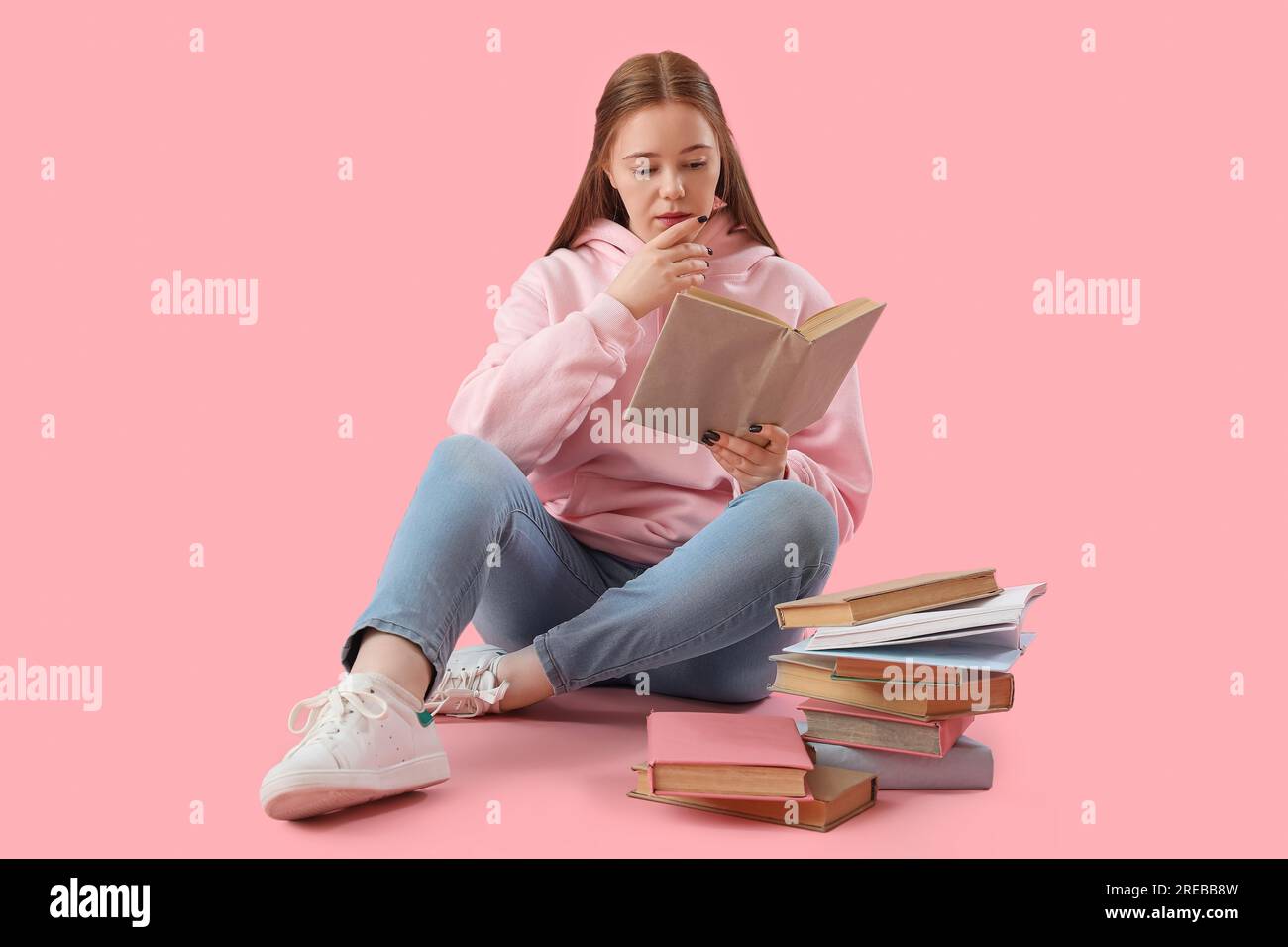 Teenage girl reading book on pink background Stock Photo - Alamy