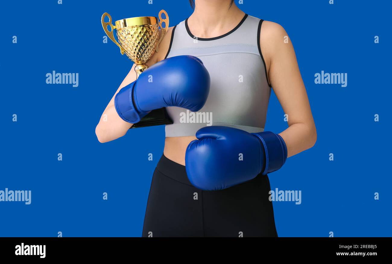 Female boxer with gold cup on blue background Stock Photo - Alamy
