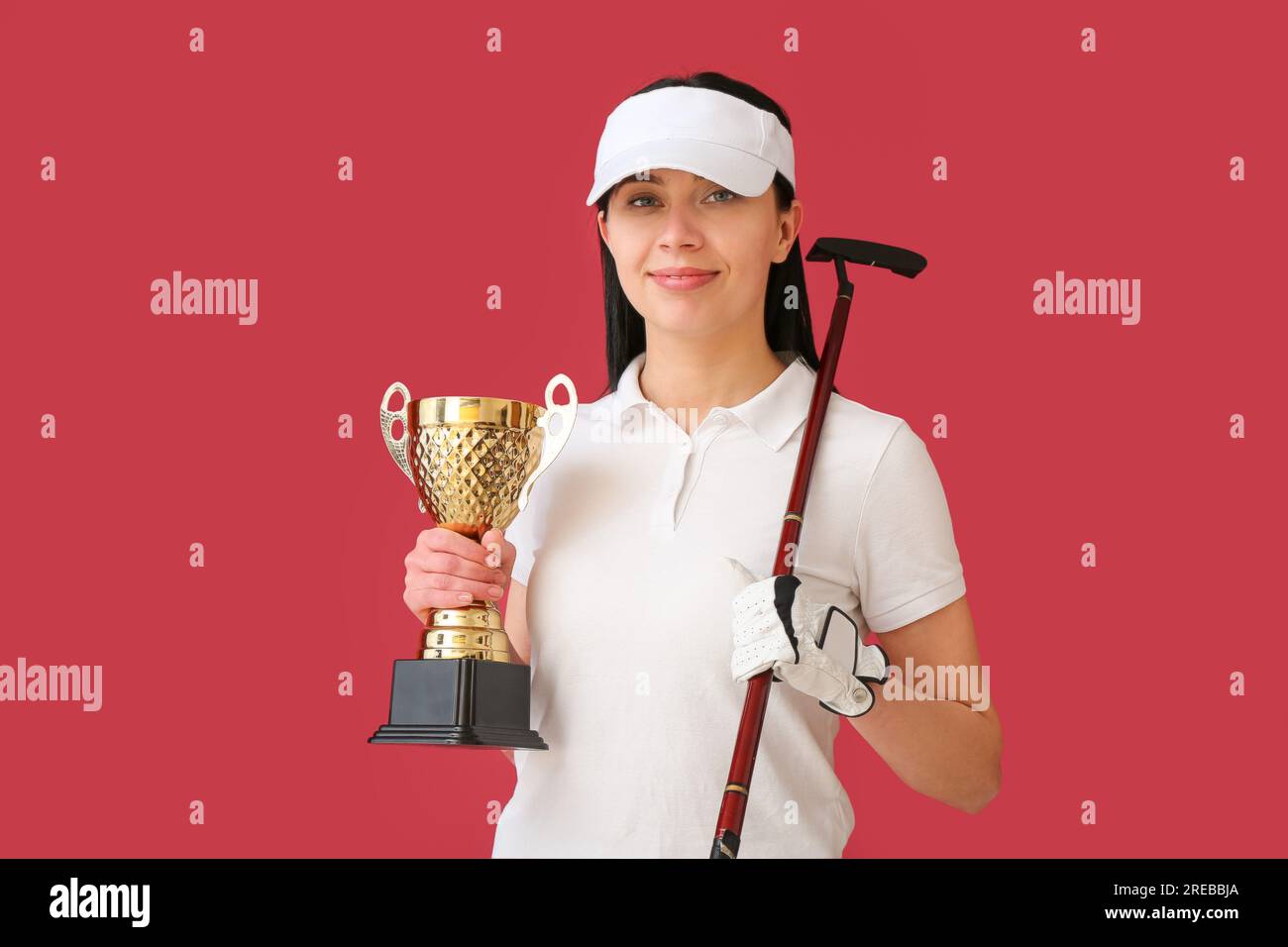 Female golfer with gold cup on red background Stock Photo - Alamy