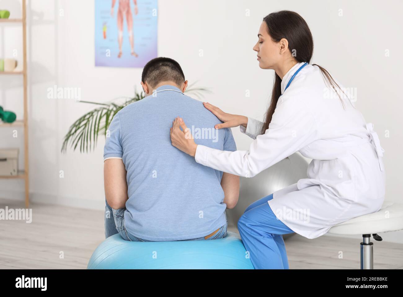 Female doctor checking posture of young man in clinic Stock Photo - Alamy