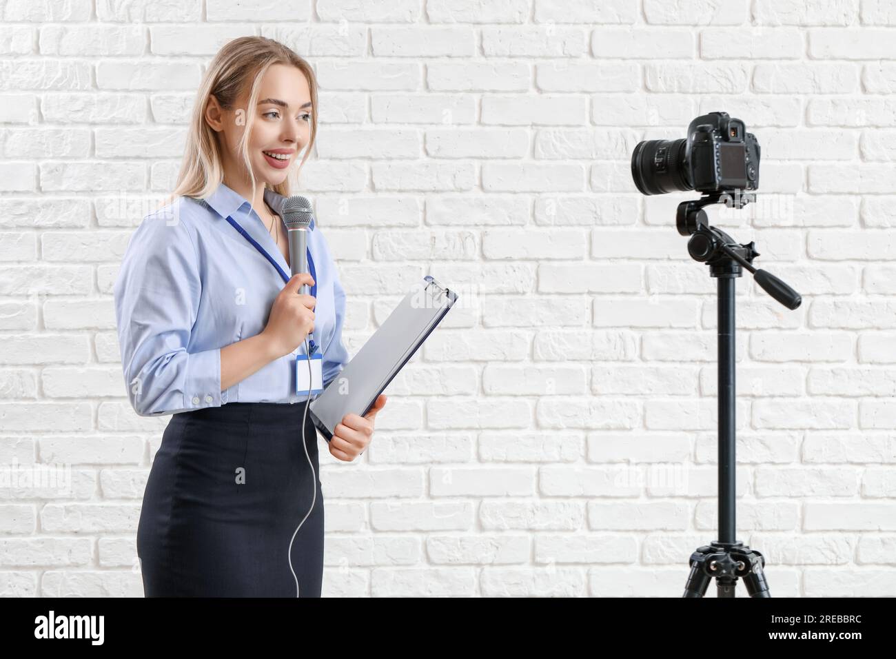 Female journalist with microphone and clipboard recording video on ...