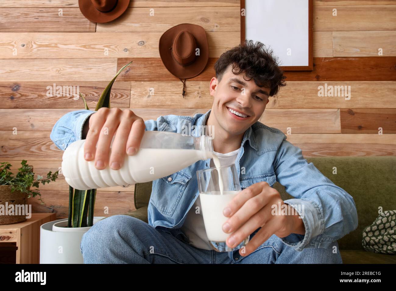 Young man pouring milk into glass at home Stock Photo - Alamy
