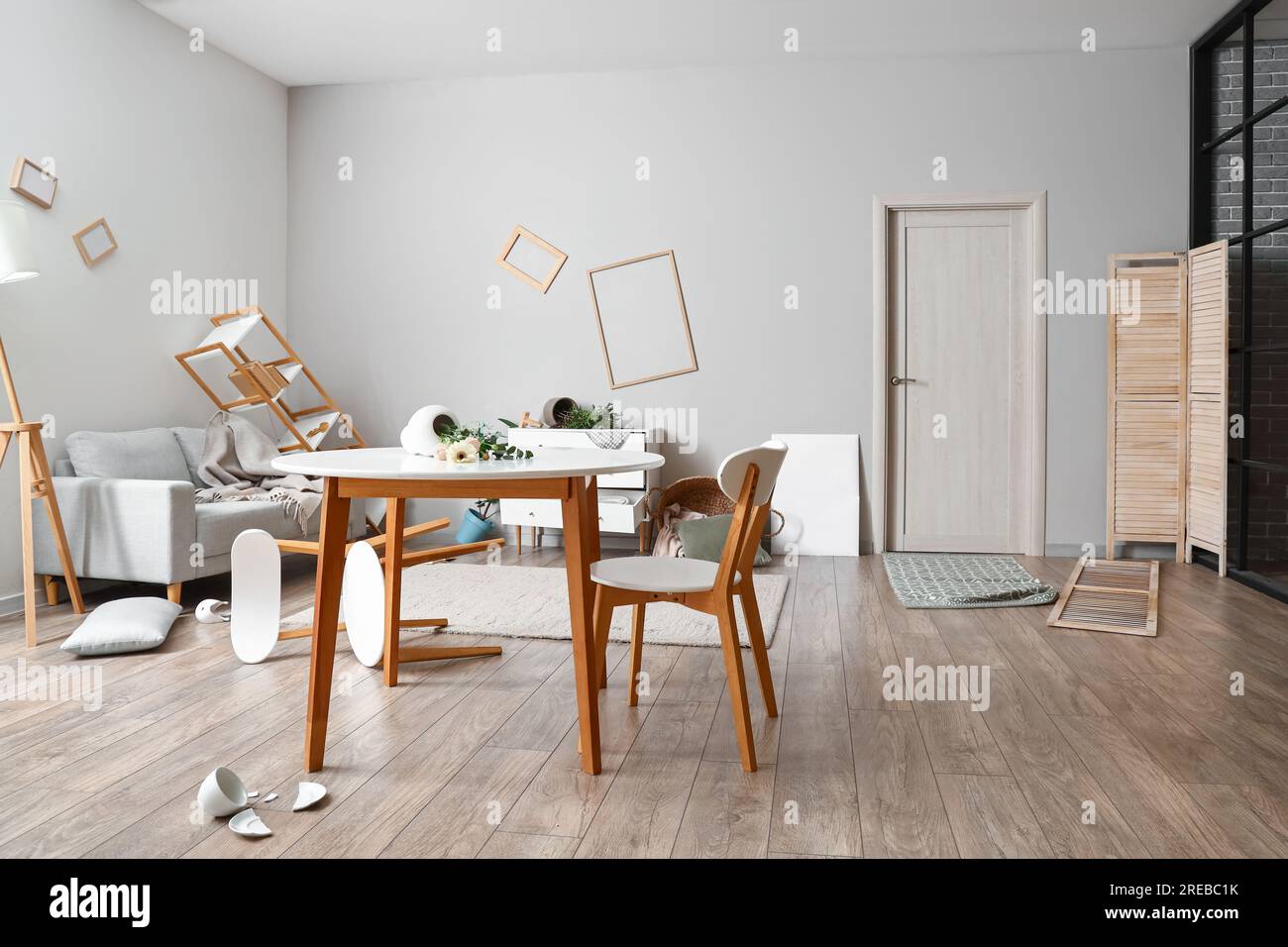 Dining table with fallen vase and flowers in messy room Stock Photo - Alamy