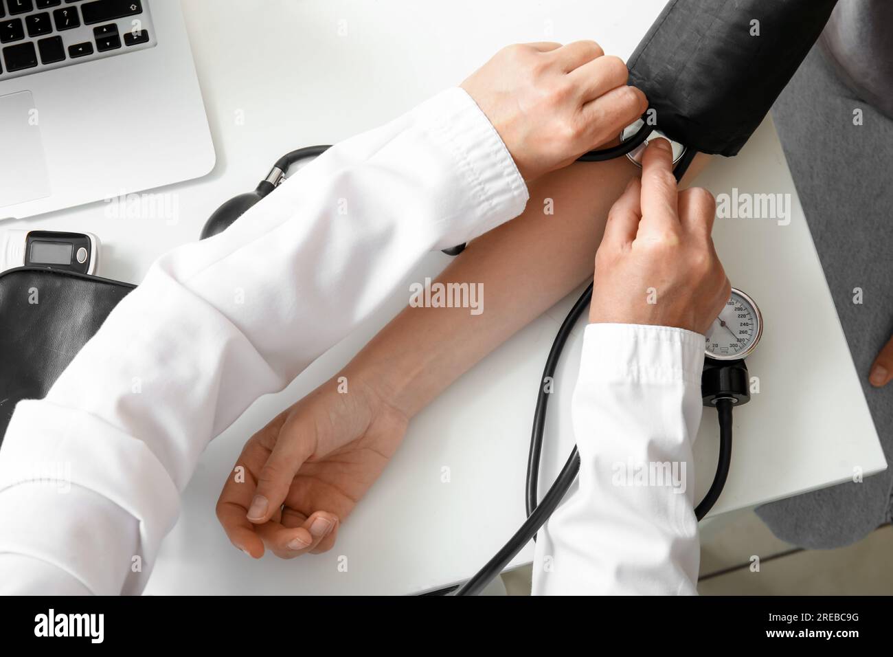 Female doctor measuring patient's blood pressure at desk in clinic, top ...