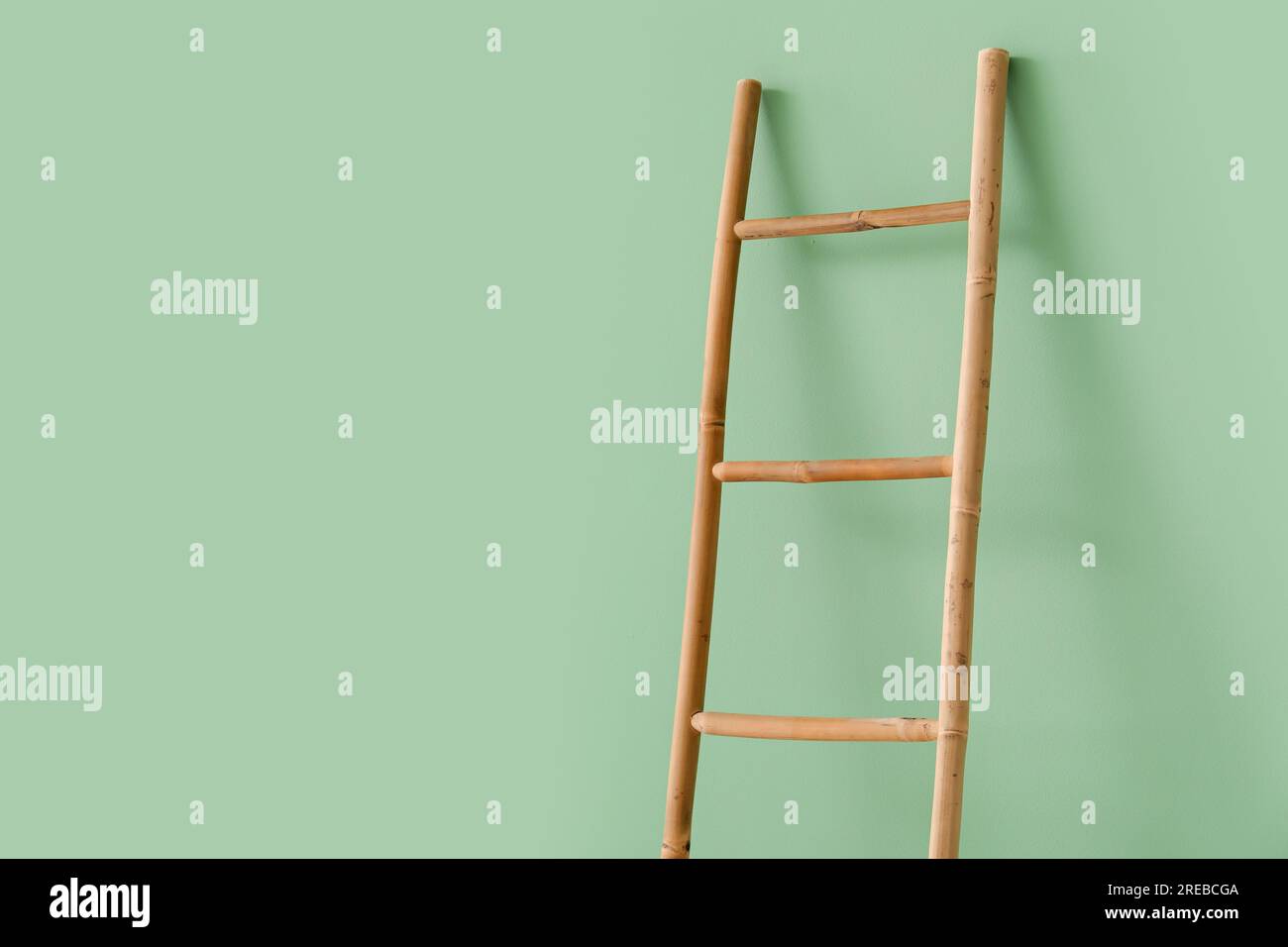 Wooden ladder near green wall in room Stock Photo - Alamy