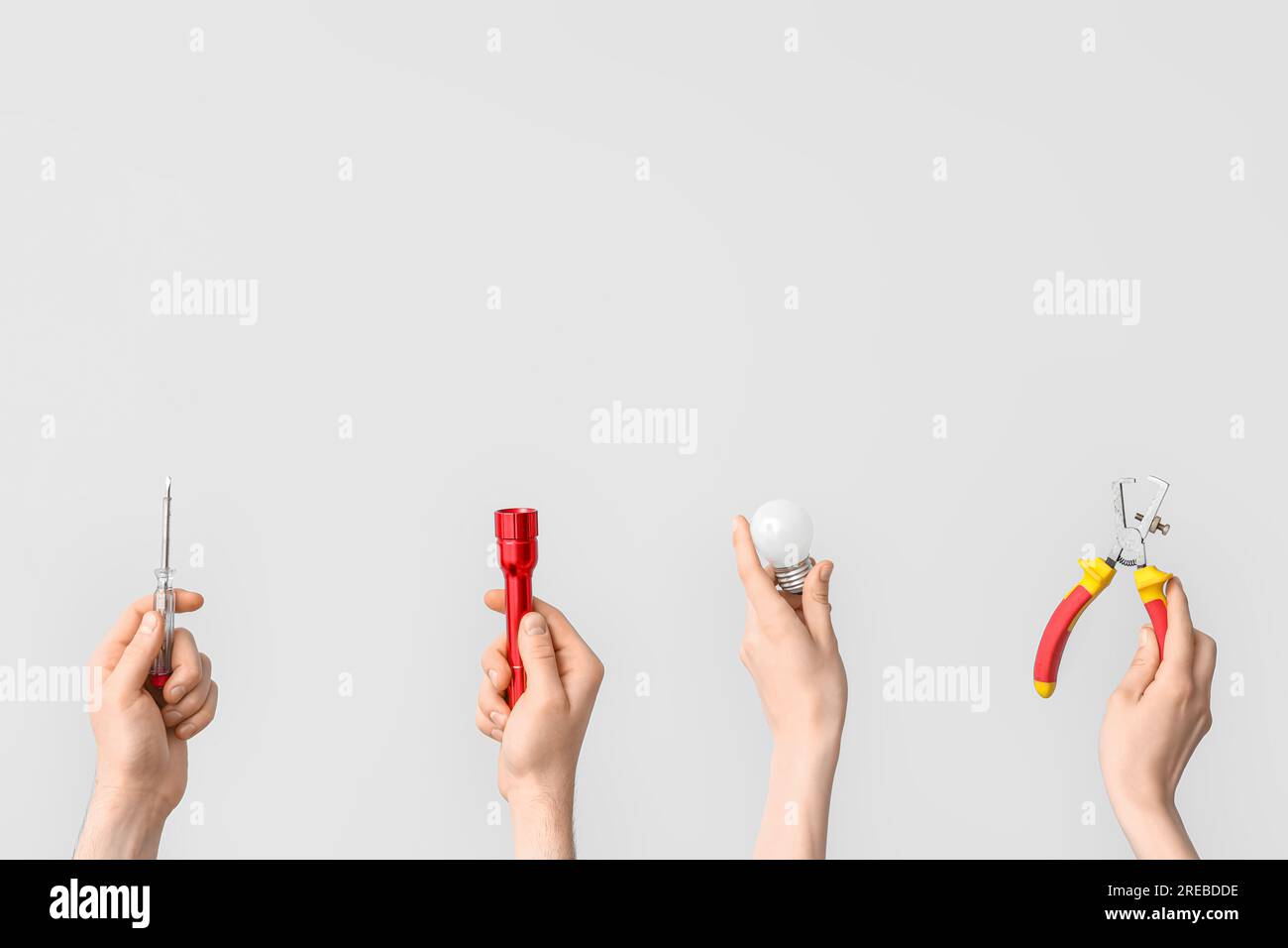 Electrician hands with light bulb and tools on grey background Stock ...