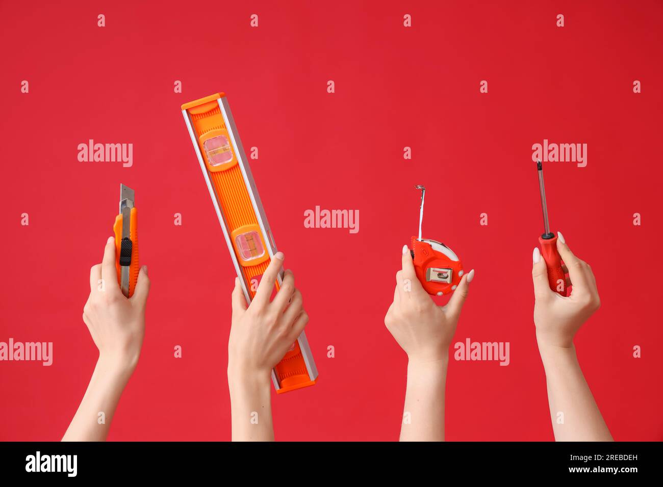 Electrician hands with tools on red background Stock Photo - Alamy