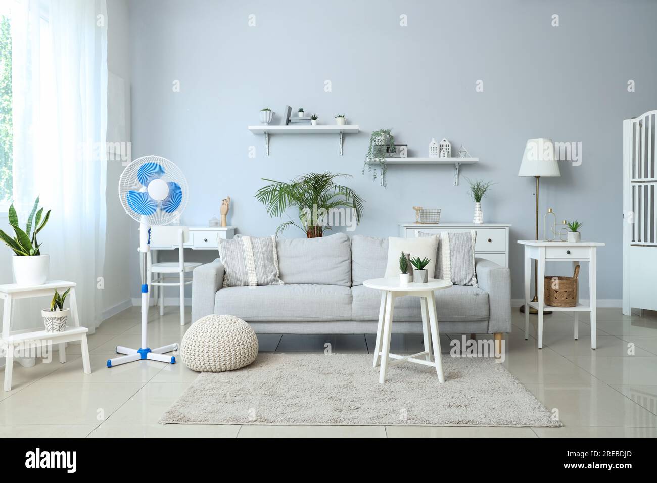 Interior of light living room with grey sofa and floor fan Stock Photo ...