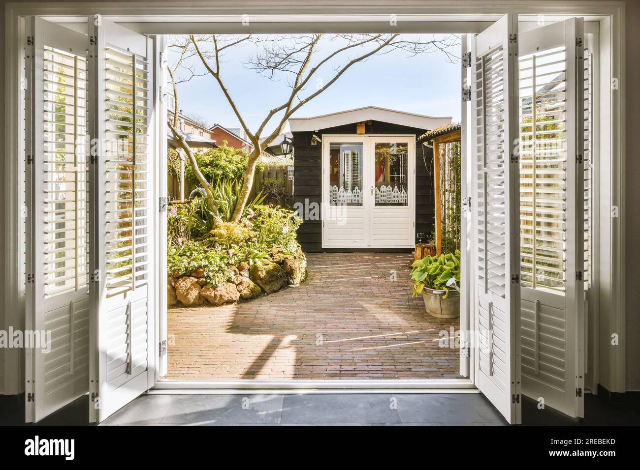 an open front door with shutters on the outside and trees in the yard ...