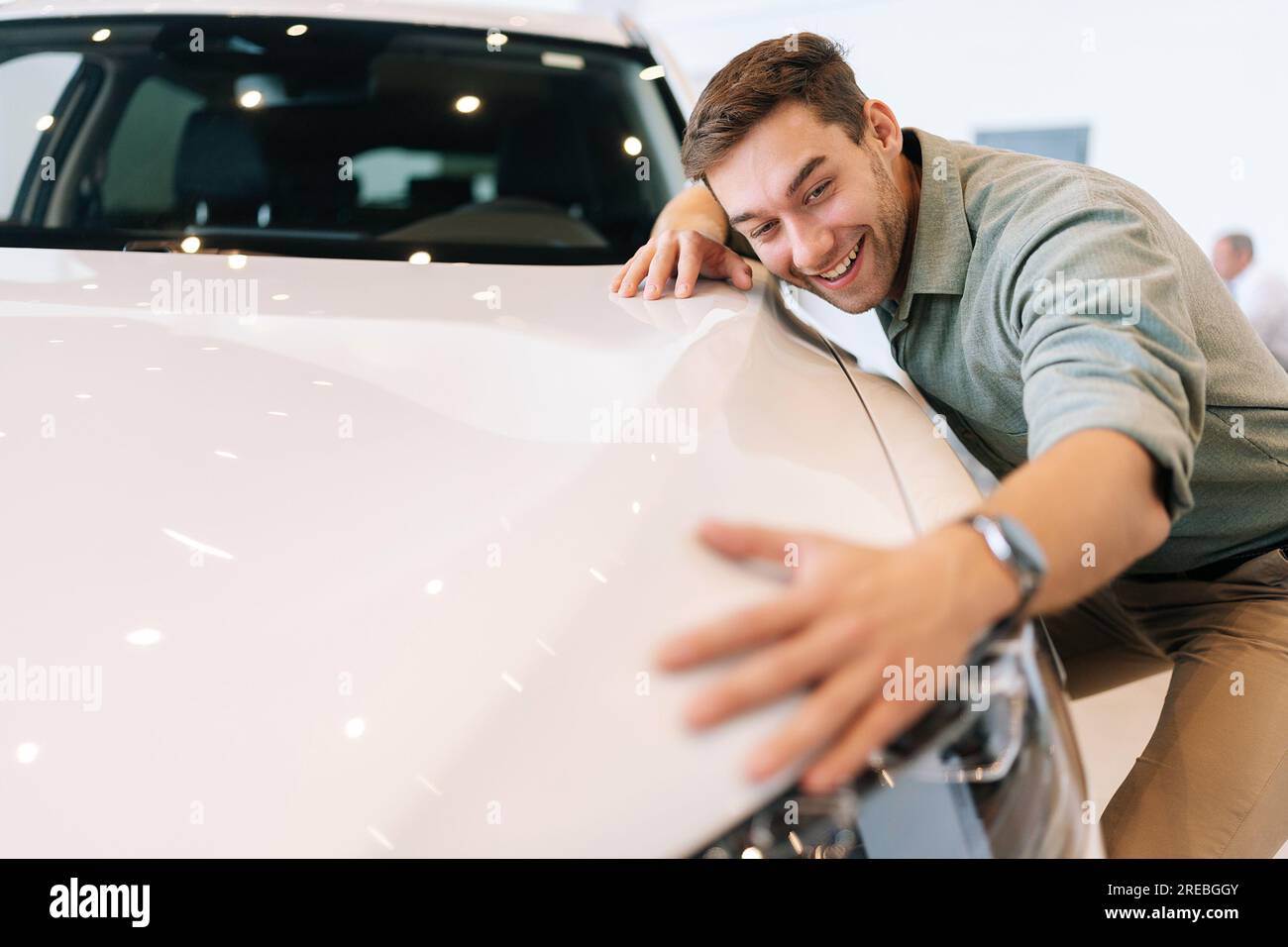 Portrait of happy smiling customer male hugging, stroking car hood ...