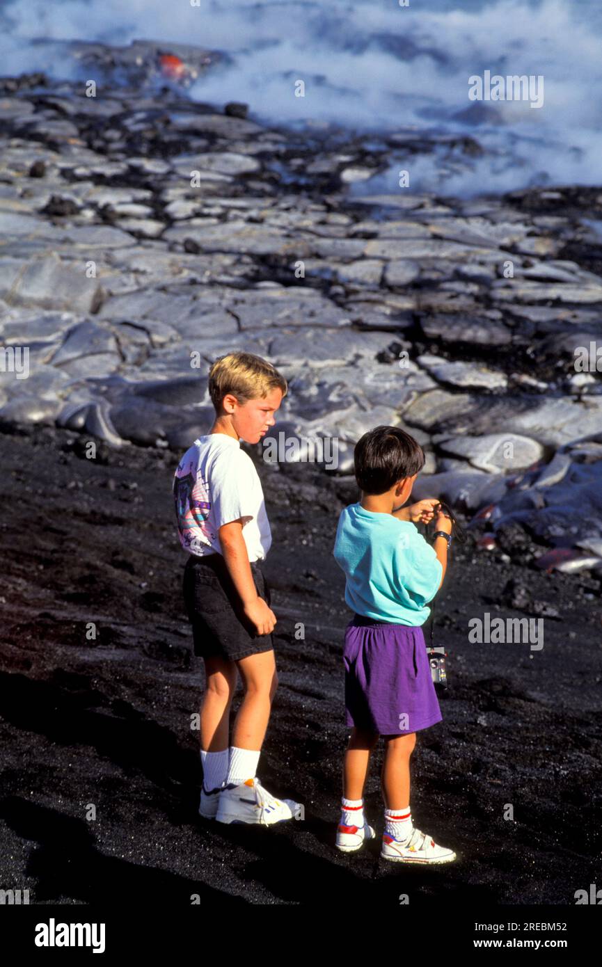 Two boys at lava flow of Kilauea volcano on the Big island of Hawaii ...
