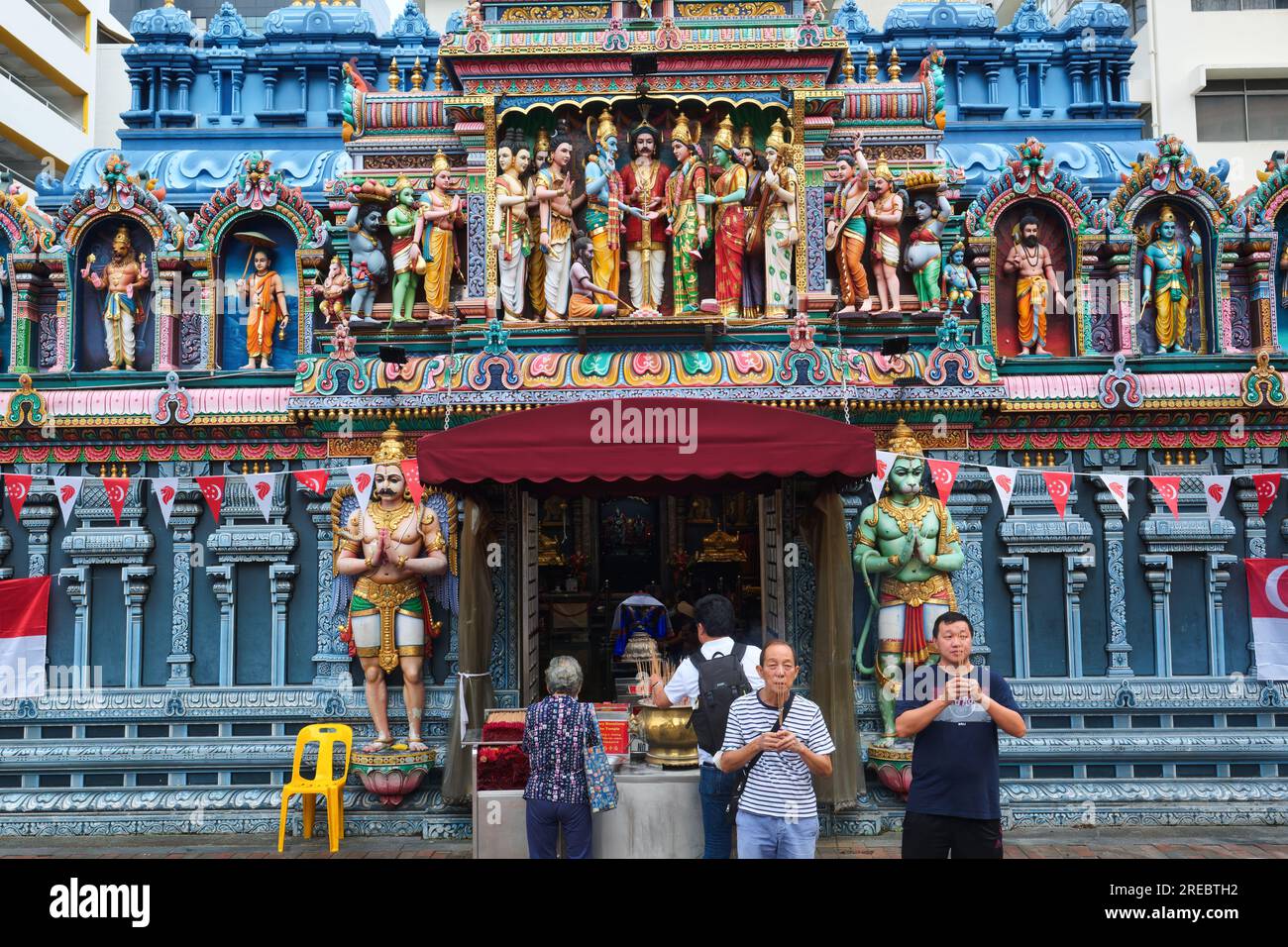 Two ethnic Chinese men praying in front of ornately decorated Sri ...