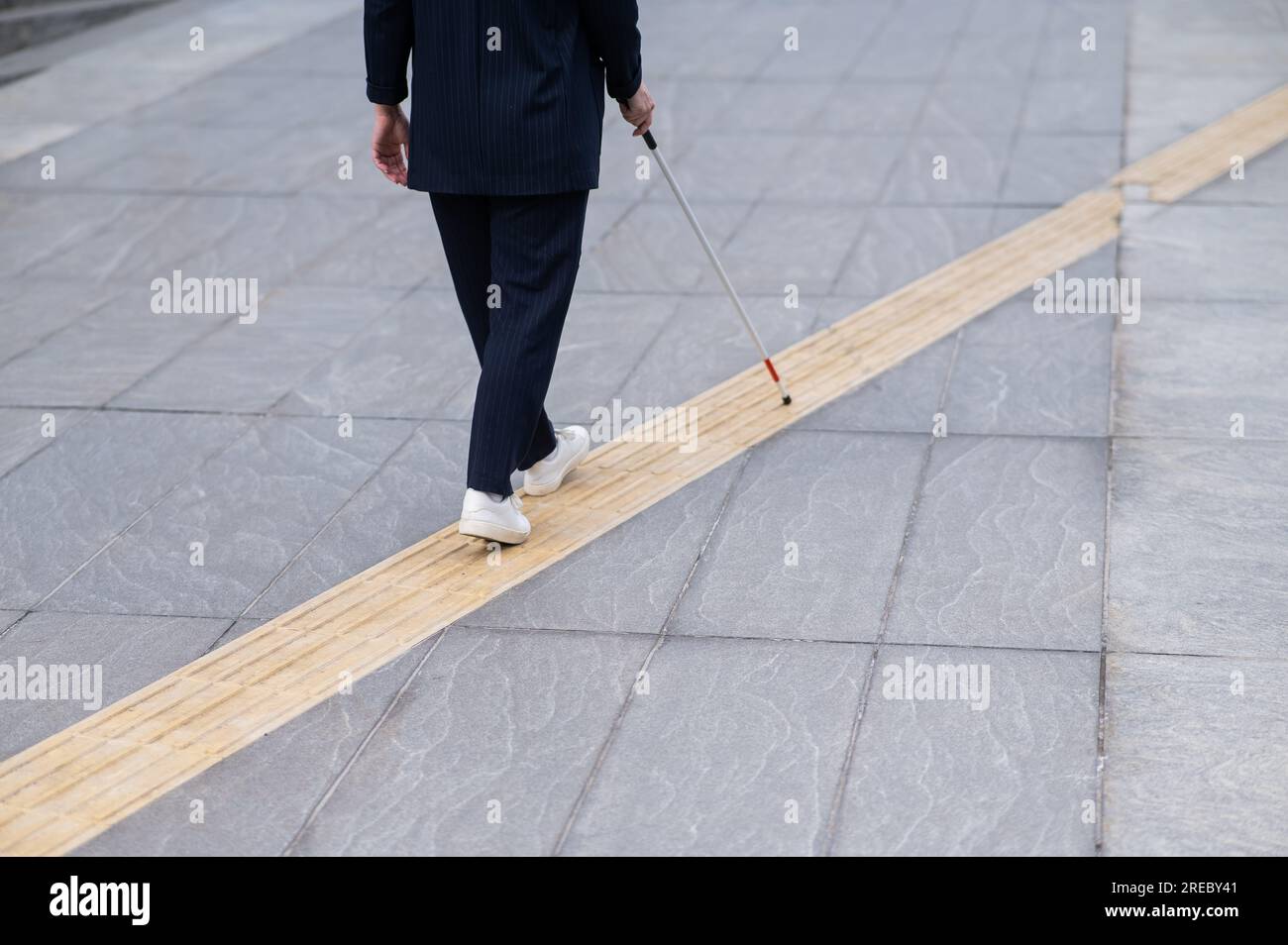 Close-up of the legs of a blind businesswoman walking along a tactile ...