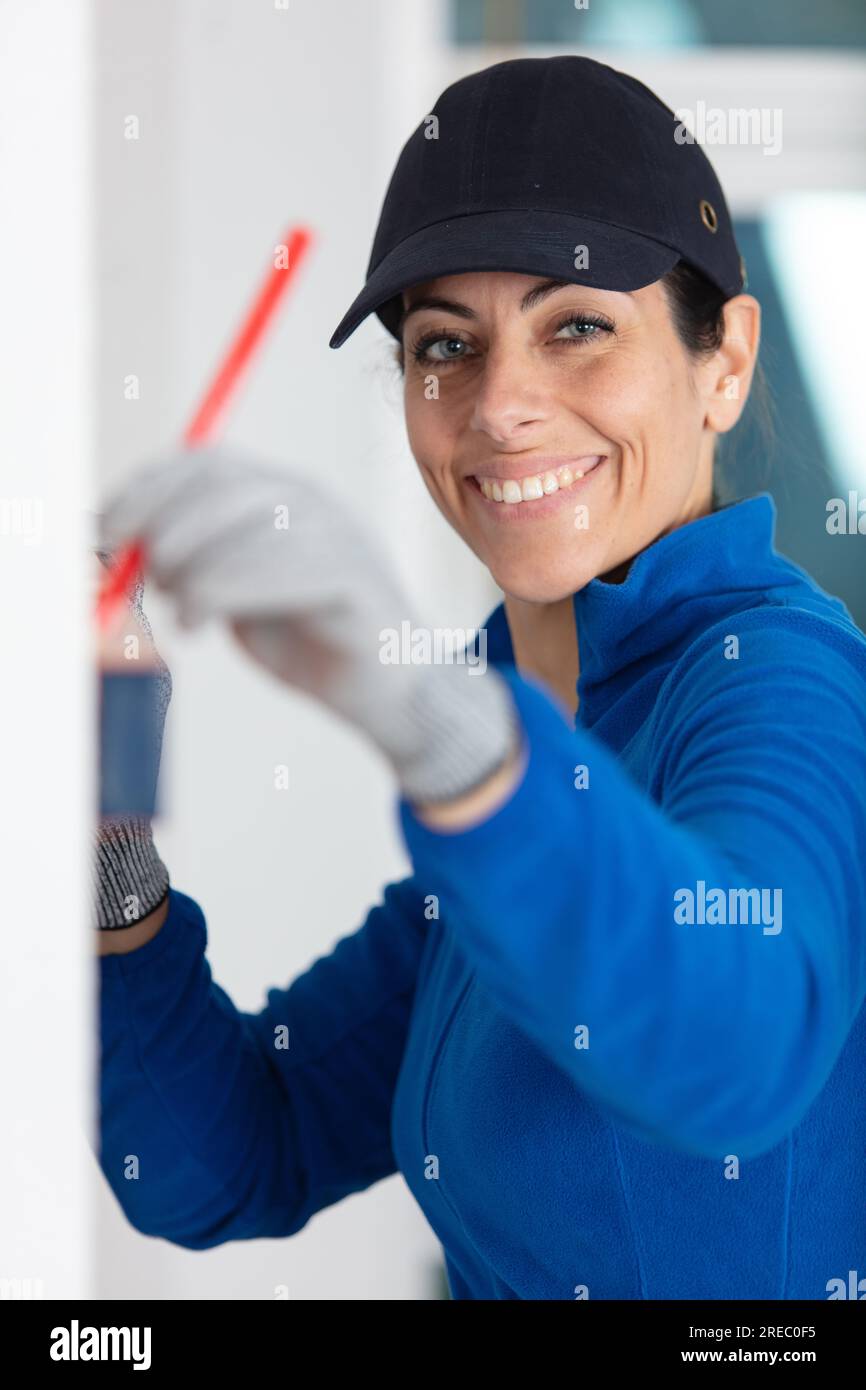 female builder drawing line above spirit level Stock Photo - Alamy