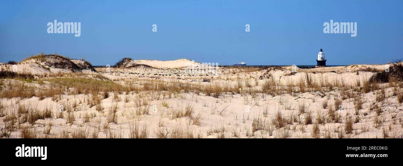 sand dunes, sea grass, coastline, and the harbor of refuge light on a ...
