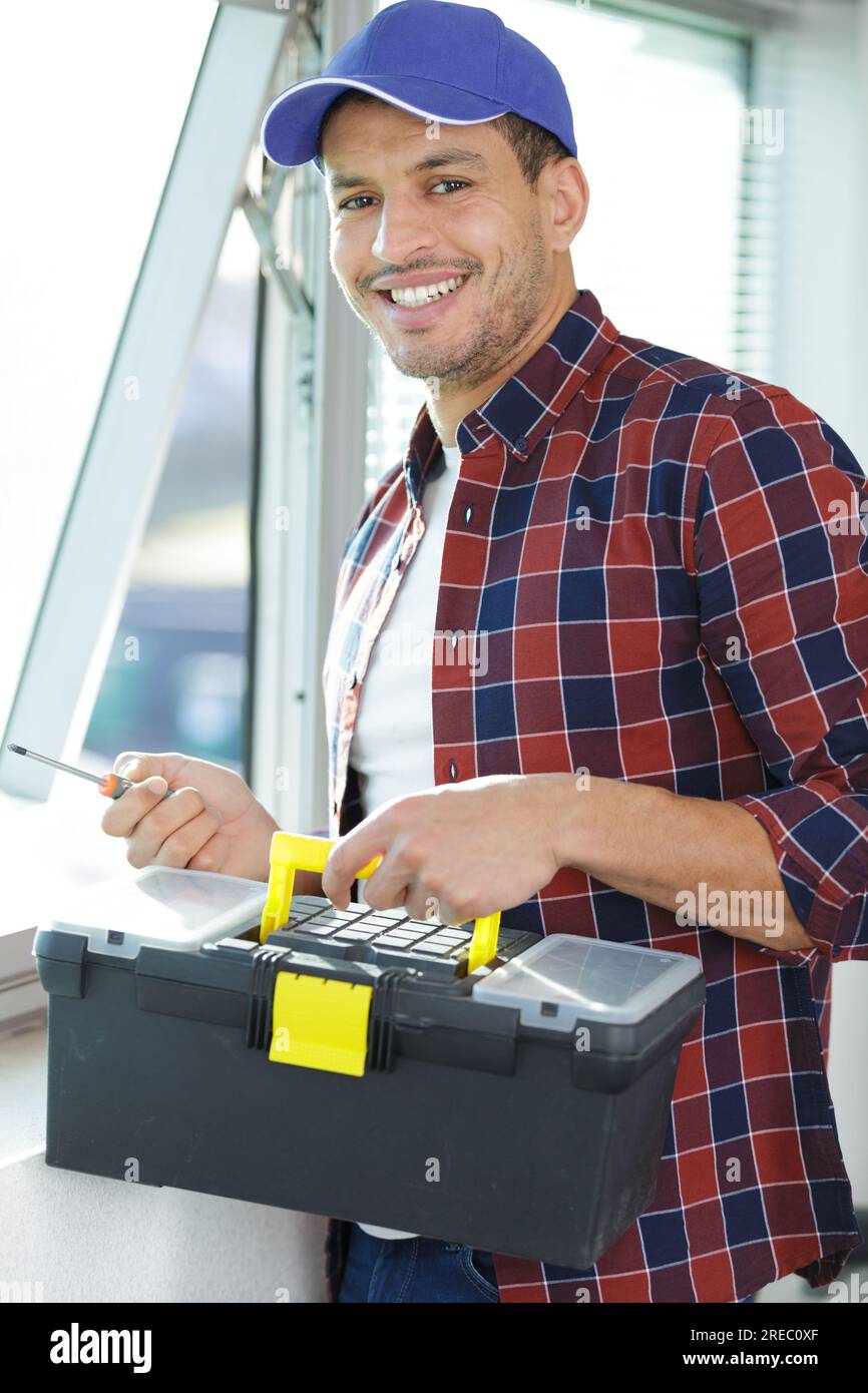 handyman holding toolbox near window Stock Photo - Alamy