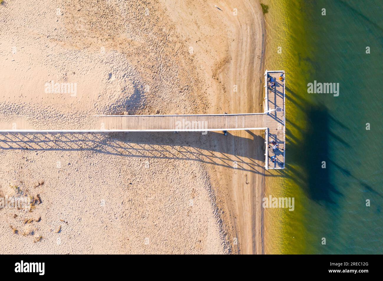 Aerial view of fishermen on a T shaped jetty crossing a sandy beach to ...