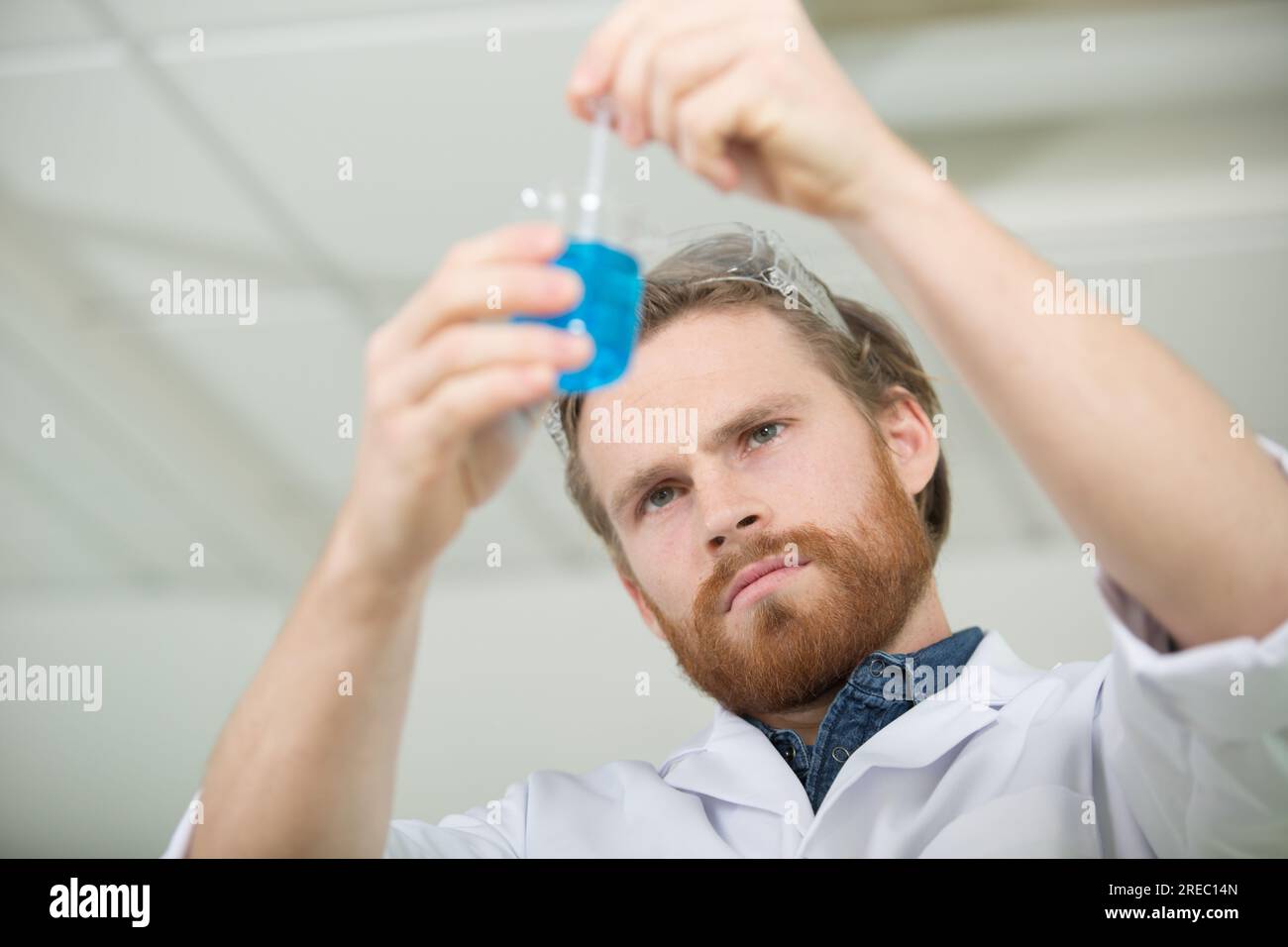 male scientist stirring liquid in a flask Stock Photo - Alamy