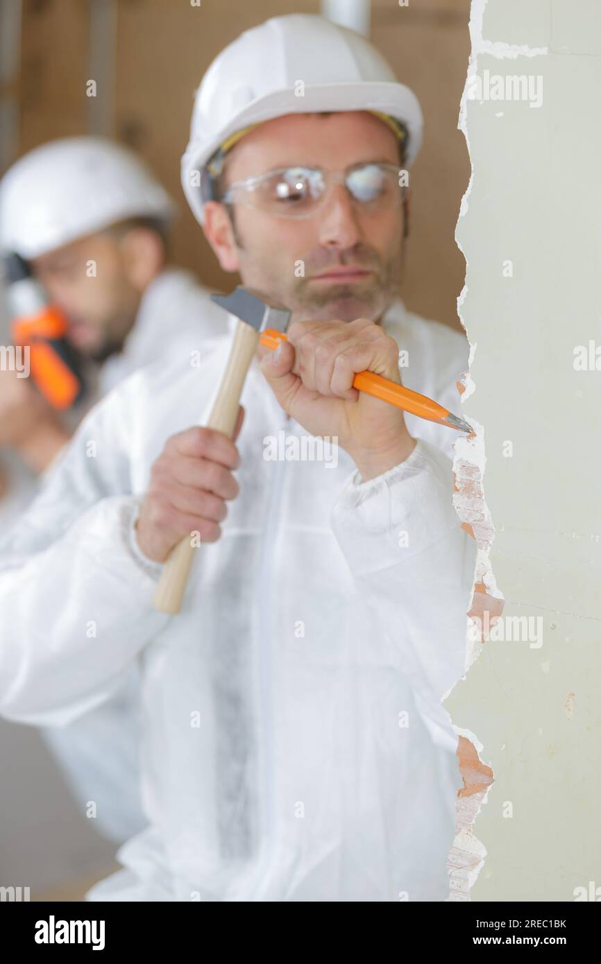 male contractor destroys brick-wall with hammer and chisel Stock Photo ...