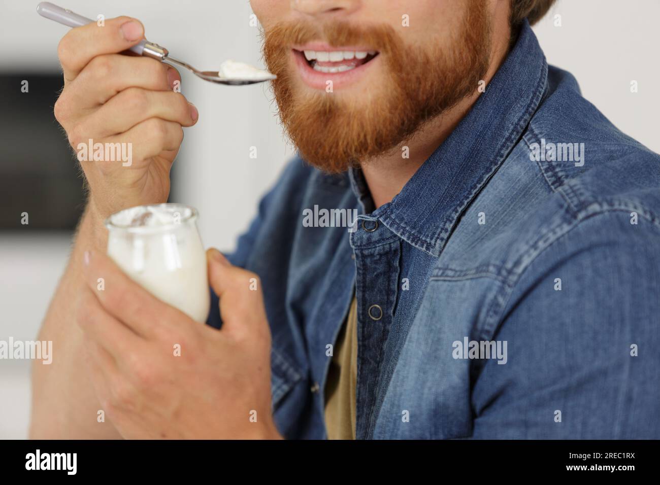 a young man eating yogurt Stock Photo - Alamy