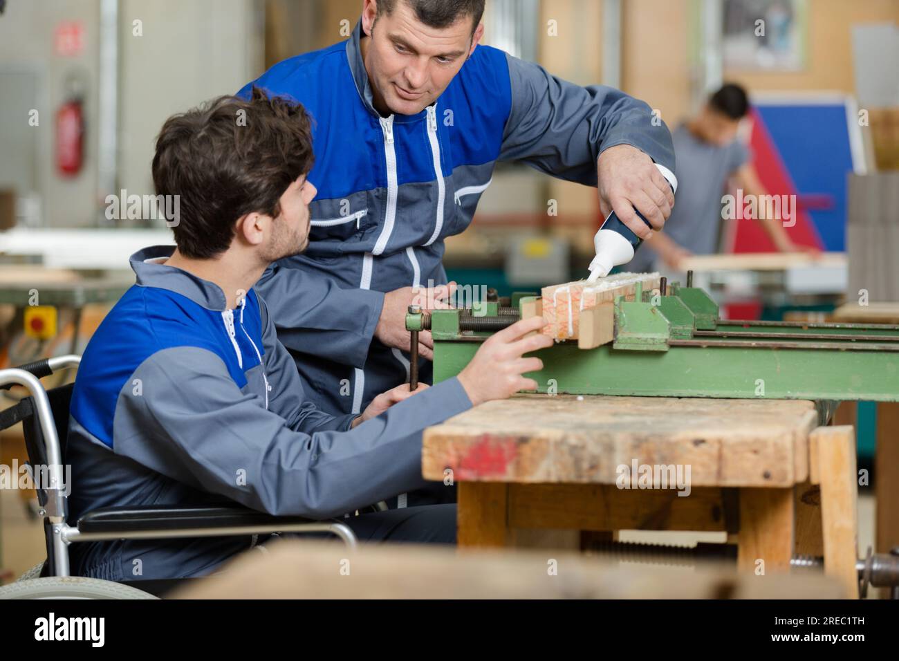 disabled worker in wheelchair in carpenters workshop with his colleague ...
