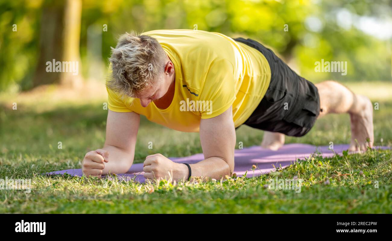 Man standing in plank position and practicing yoga outdoors at summer ...