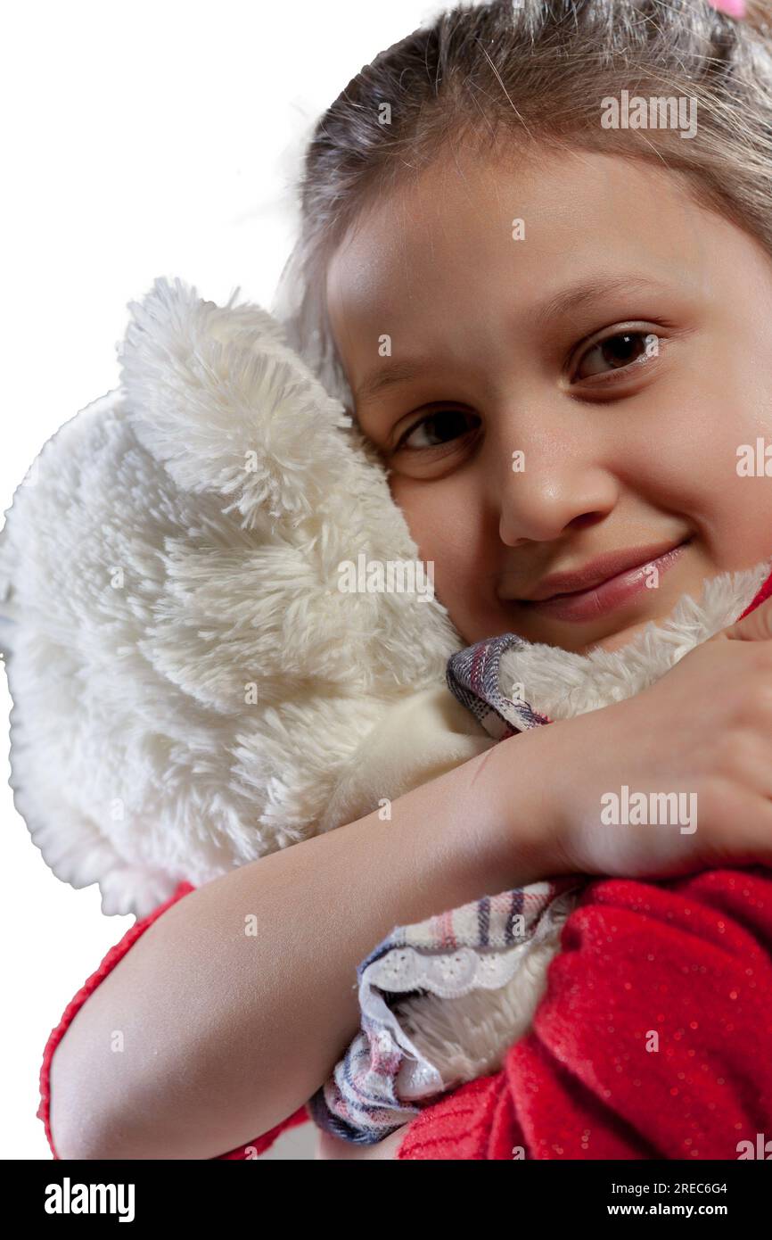 Girl in a red sweater loves her white teddy bear, plays with it ...