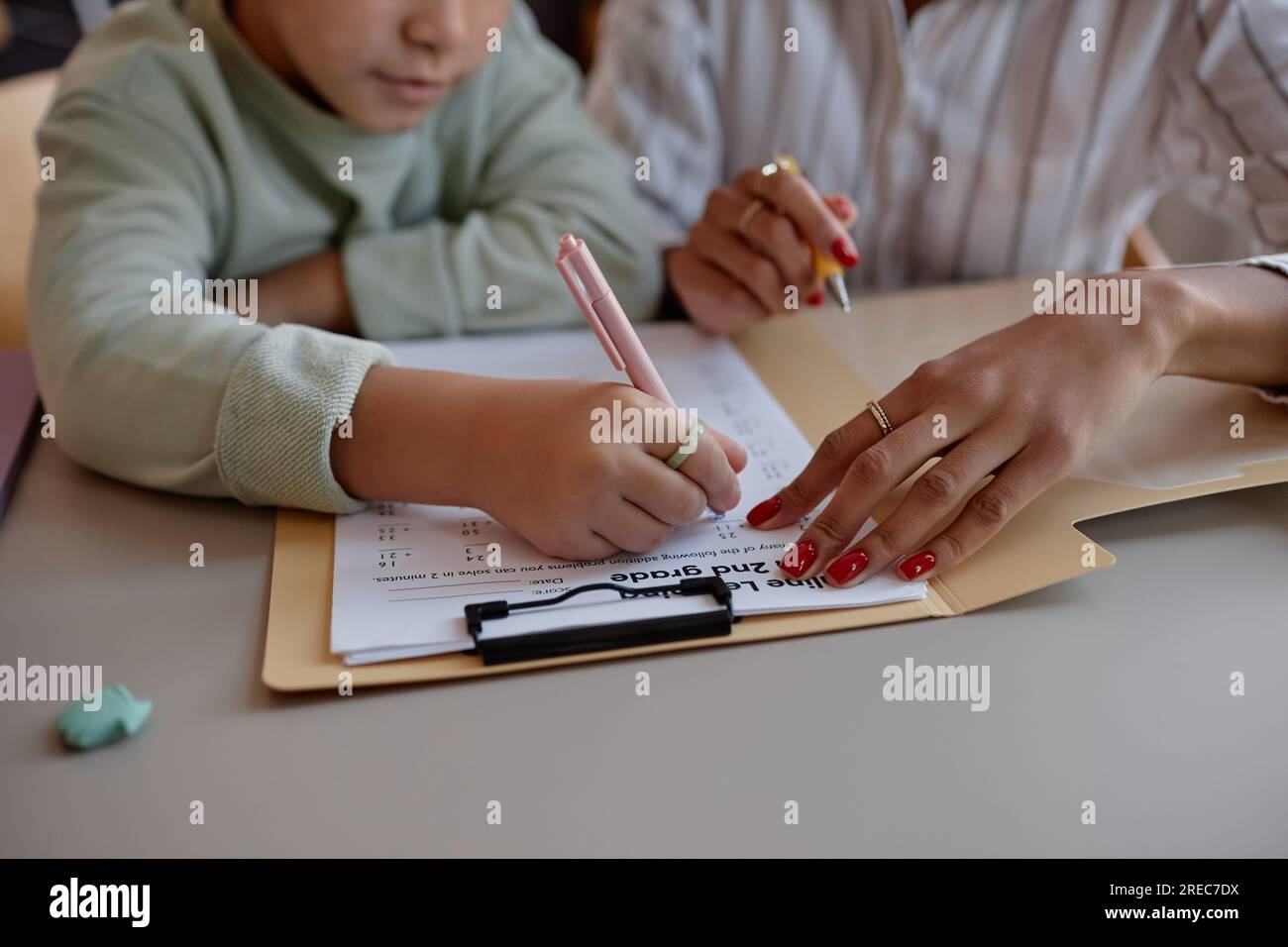 Closeup of little black girl doing math test at home with mother of ...
