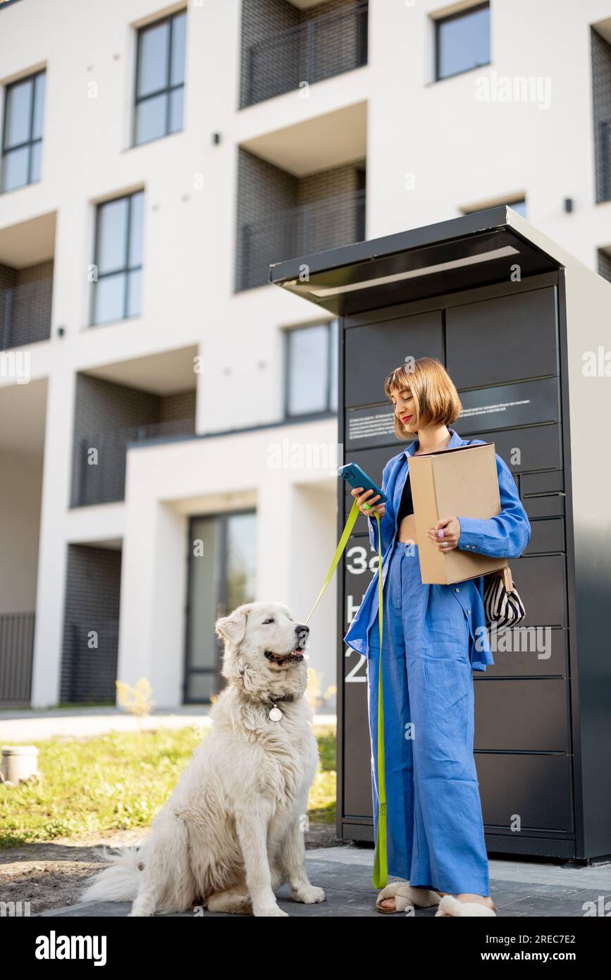 Woman with her dog picks up parcels from automatic post office machine ...