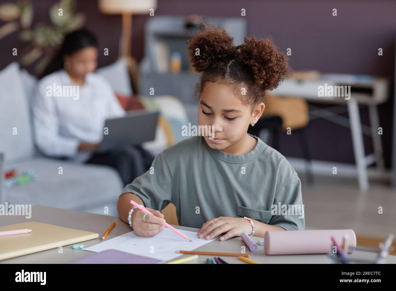 Portrait of black girl drawing pictures sitting at table at home and ...