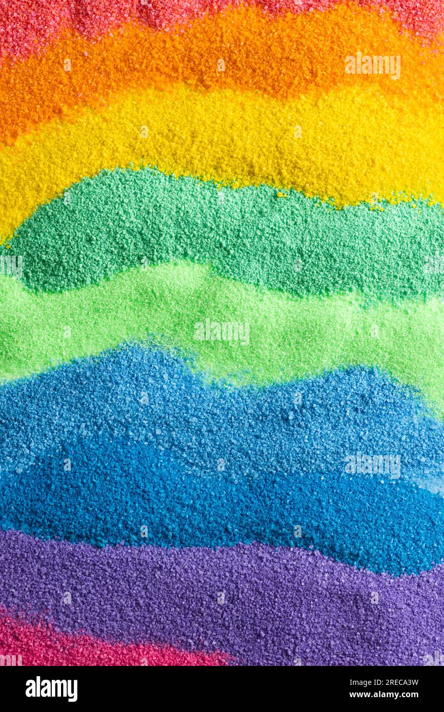 Close up of stripes of rainbow coloured sand and copy space background ...