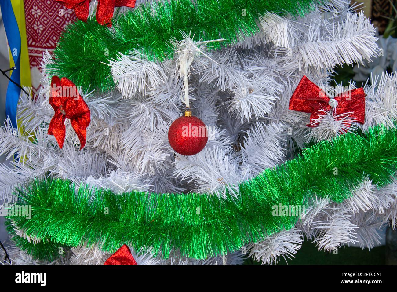 Beautiful white Christmas tree closeup with red ball and green tinsel ...