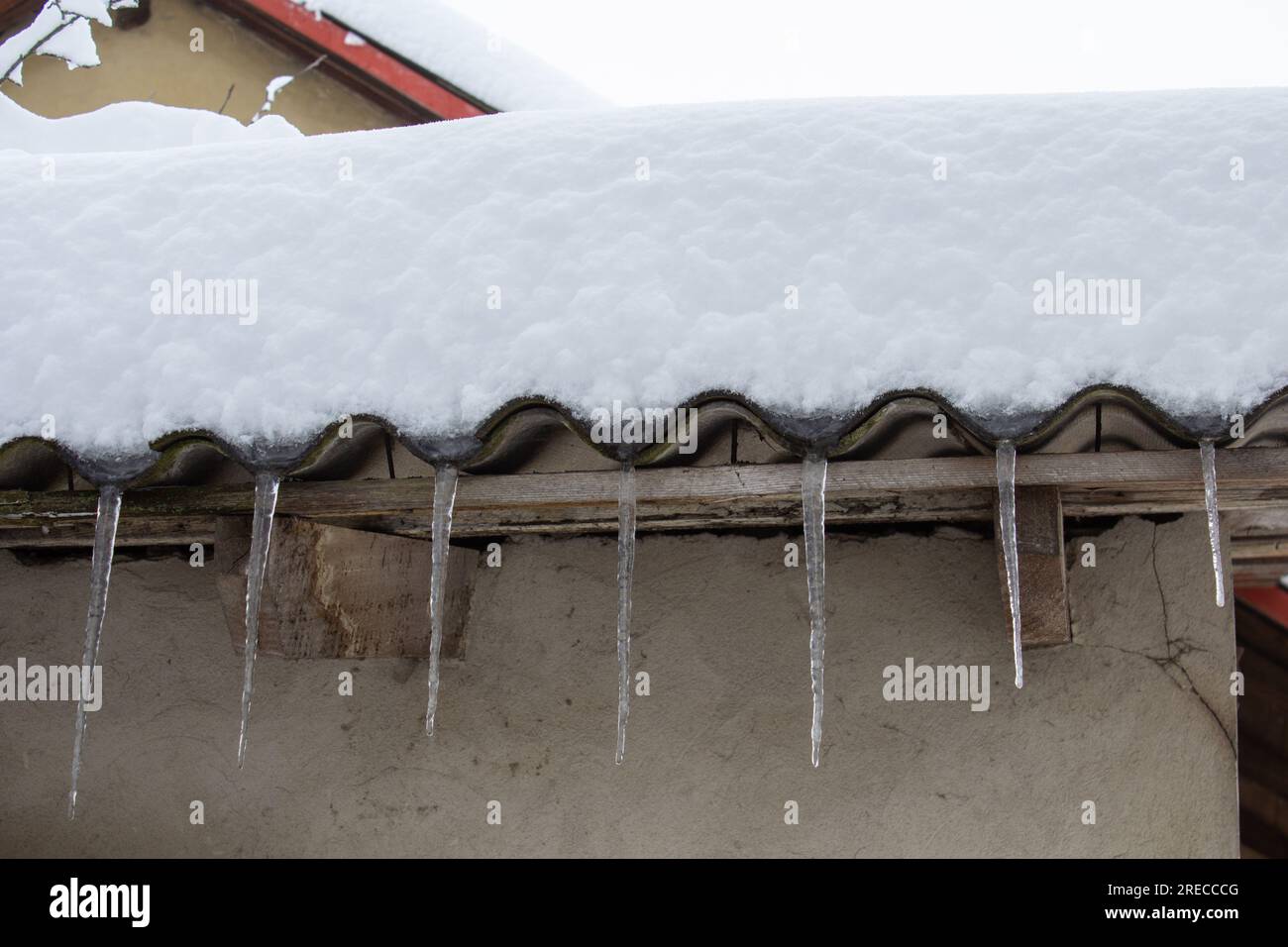 snow and icicles hanging on the old slate roof, hanging icicles from the roof Stock Photo - Alamy