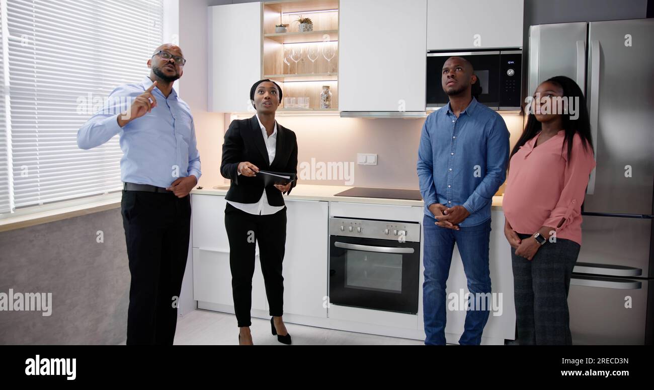 Real Estate Agent Showing House Kitchen To A Young Couple Stock Photo ...