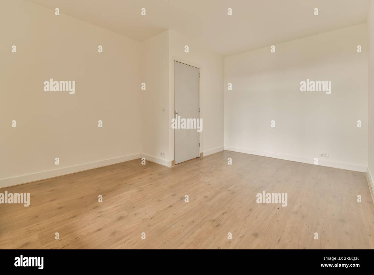 an empty room with wood floors and white walls, there is a door leading ...