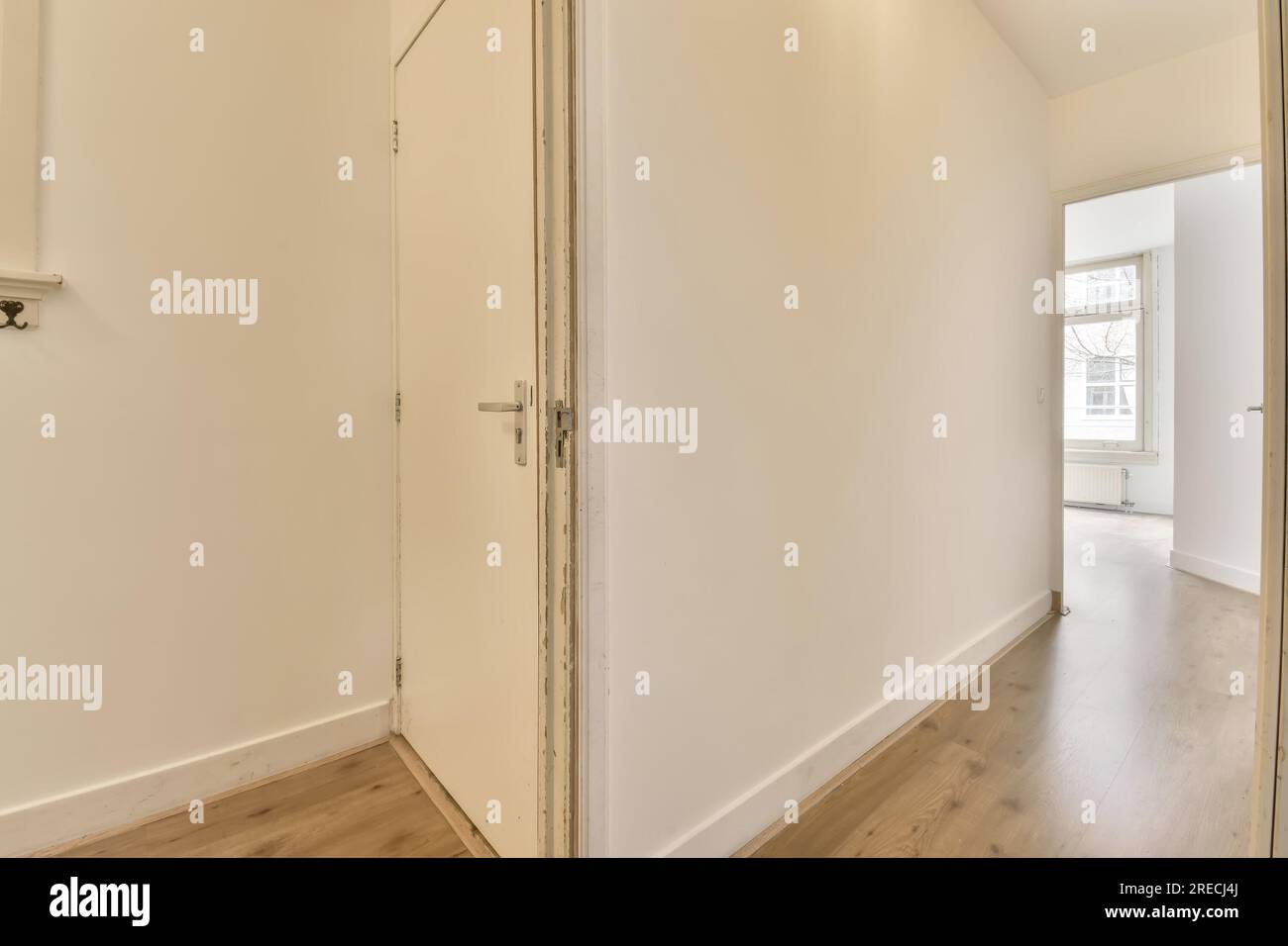 an empty room with wood floors and white walls, there is a large mirror ...